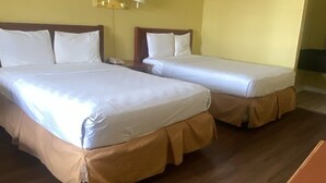 Quarto de hotel com duas camas, piso de madeira e uma pequena mesa.