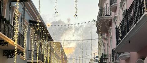 Rua ladeada por edifícios, decorada com luzes de Natal.