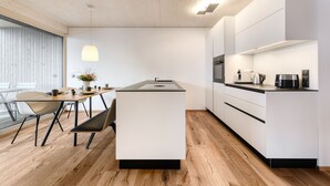 Cozinha moderna com ilha central, piso de madeira e armários brancos.