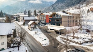 Um edifício moderno com telhado plano, área de estacionamento coberta e rua coberta de neve.