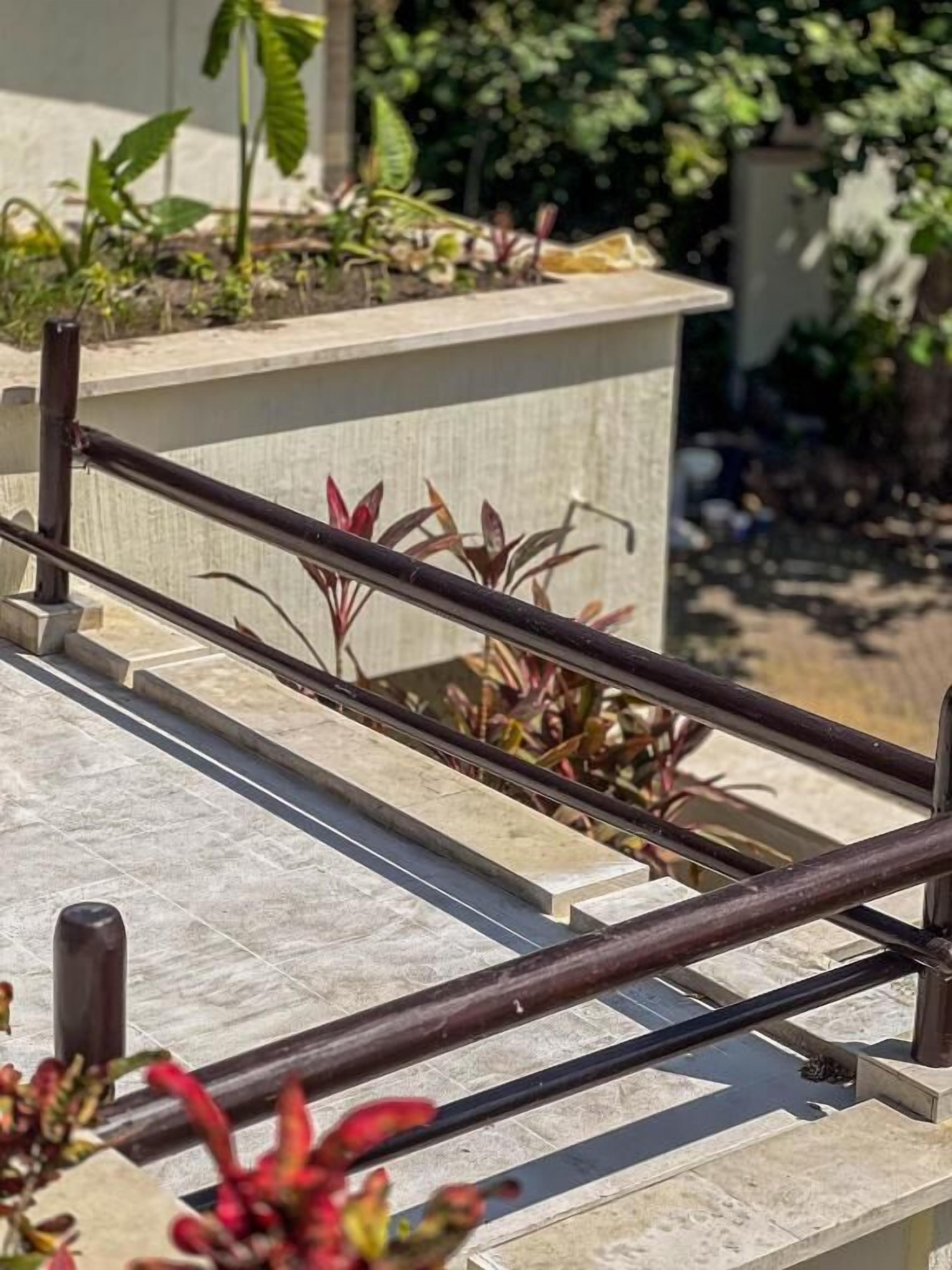 Escadaria de concreto com corrimãos de metal, cercada por vegetação.