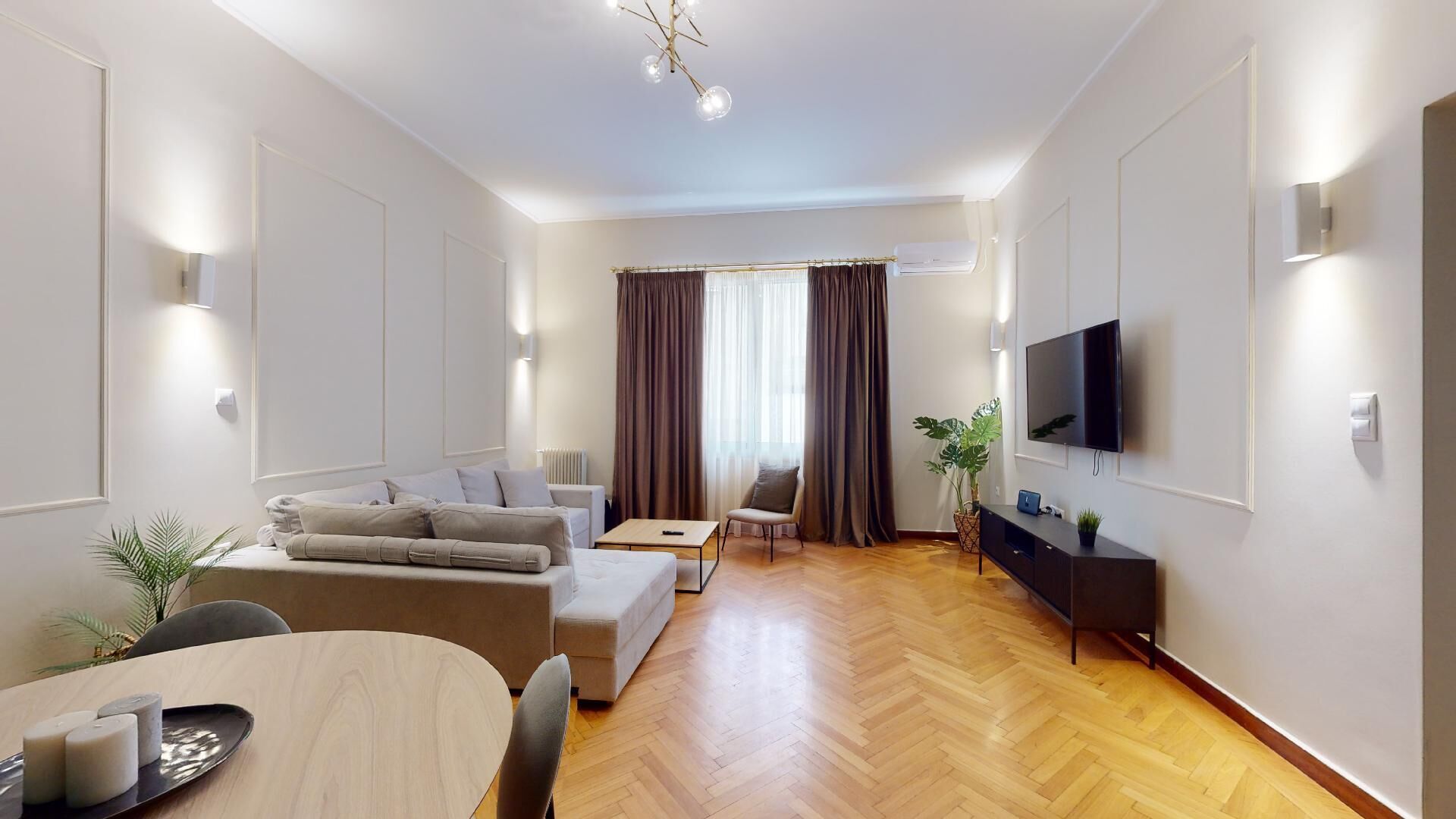 Uma sala de estar moderna com sofá, mesa de centro, televisão e área de jantar com mesa e cadeiras.