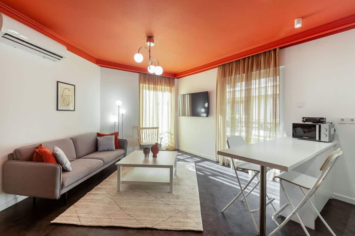 Uma sala de estar moderna com sofá, mesa de centro e área de jantar com mesa e cadeiras.