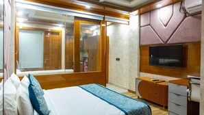 Quarto com cama, televisão na parede, guarda-roupa e espelho.