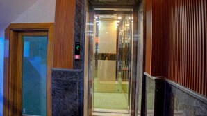 Um elevador com painel digital, revestimento de madeira e porta de vidro.