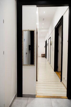 Corredor com espelho, piso de madeira e portas que dão para os quartos.