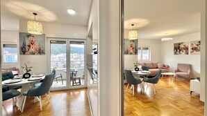 Uma sala de estar moderna com área de jantar, janelas amplas e obras de arte nas paredes.