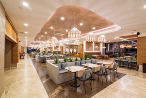 Restaurante moderno com pé-direito alto, lustres pendentes e diversos tipos de assentos, incluindo cabines e mesas.