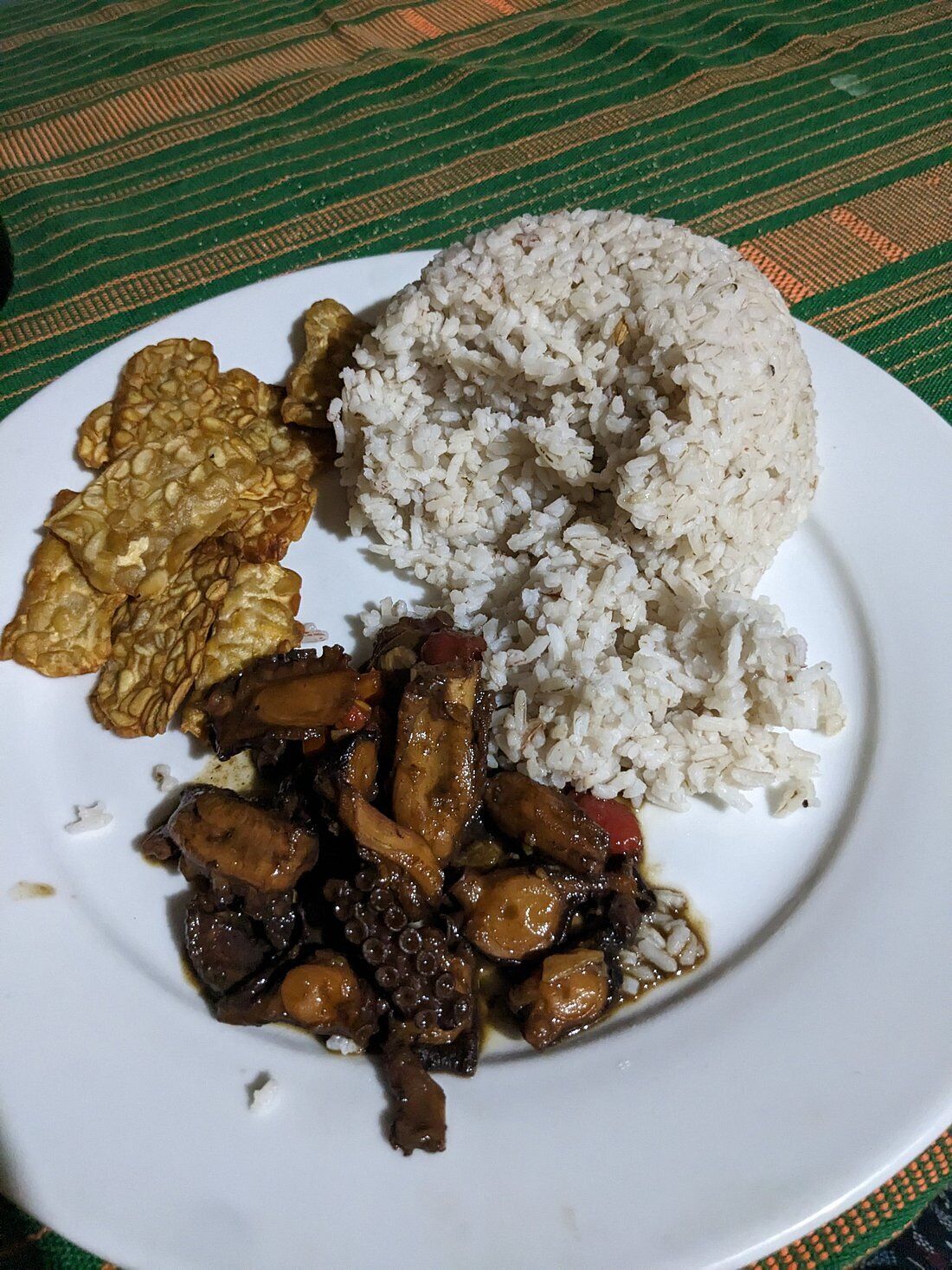 Um prato com arroz branco, bananas à milanesa e um refogado.