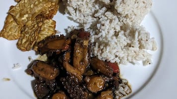 Um prato com arroz branco, bananas à milanesa e um refogado.