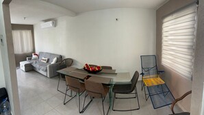 Um espaço compacto com área de jantar, sofá e janela com persianas.