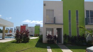 Um edifício moderno com fachada verde e branca, entrada visível e gramado bem cuidado.