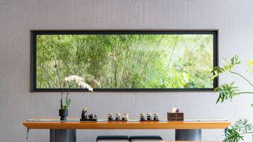 Quarto moderno com uma janela grande, uma escrivaninha de madeira, duas cadeiras e uma orquídea em vaso.