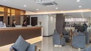 Um lobby moderno de hotel com balcão de recepção, área de estar e bar.