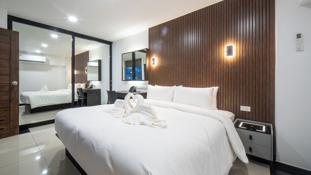 Quarto de hotel moderno com uma cama grande, uma escrivaninha e um espelho.
