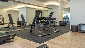 Uma academia moderna com equipamentos de exercícios, um espelho na parede e um aparelho de ar condicionado no teto.