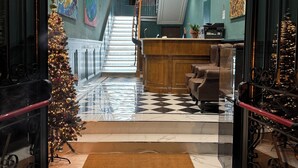 Um hall de entrada com uma árvore de Natal, piso xadrez, escada e balcão de recepção.
