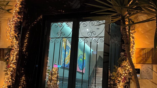 A entrada do Hotel Modi com um arco decorativo e um pinheiro de Natal.