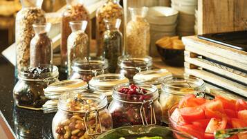 Mesa de buffet com diversos alimentos, incluindo potes de nozes, frutas secas e legumes fatiados.