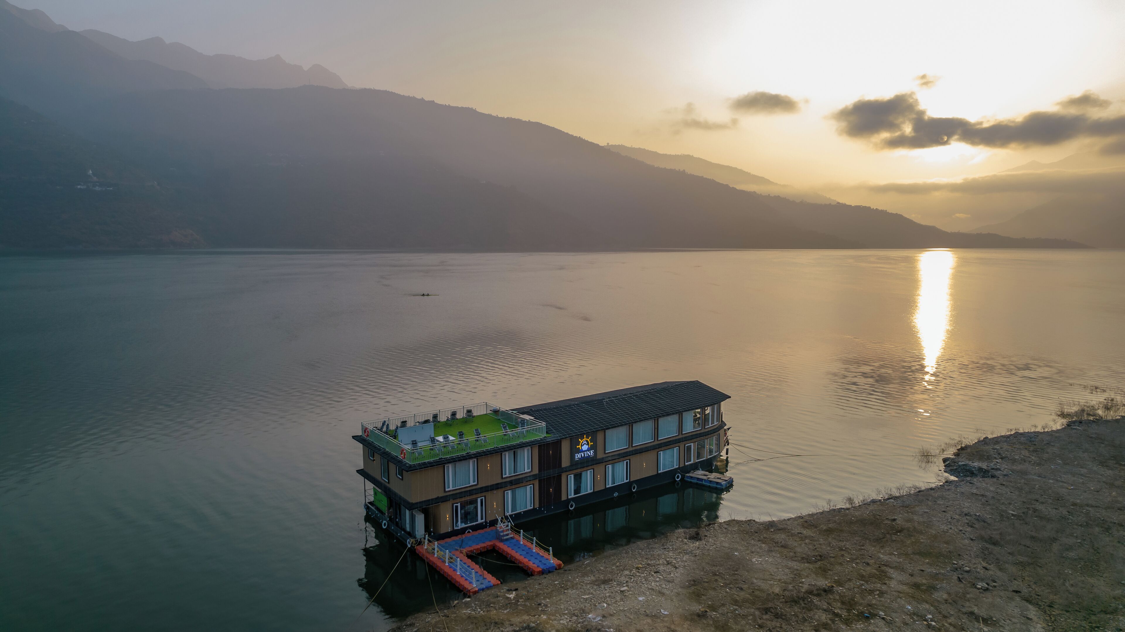 Um hotel flutuante com um deque e um pequeno barco atracado nas proximidades.