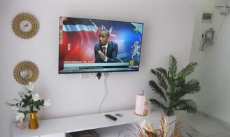 Uma televisão presa na parede exibindo uma transmissão de notícias.