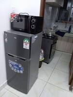 Cozinha compacta com geladeira, fogão e micro-ondas.