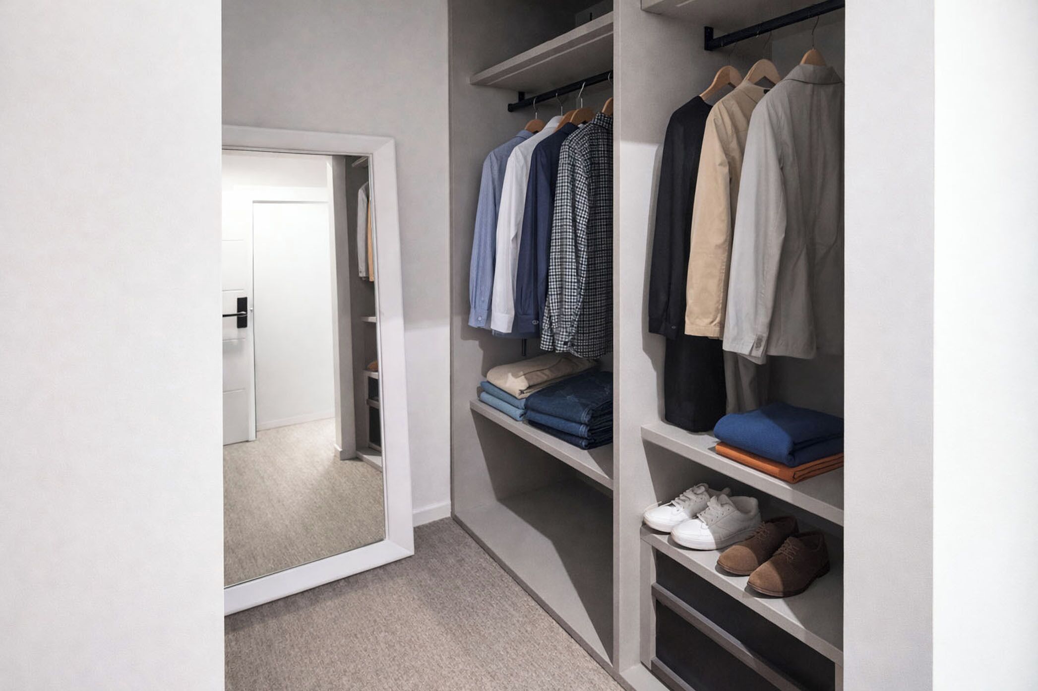 Um closet amplo com roupas penduradas, calças jeans dobradas e prateleiras com sapatos.