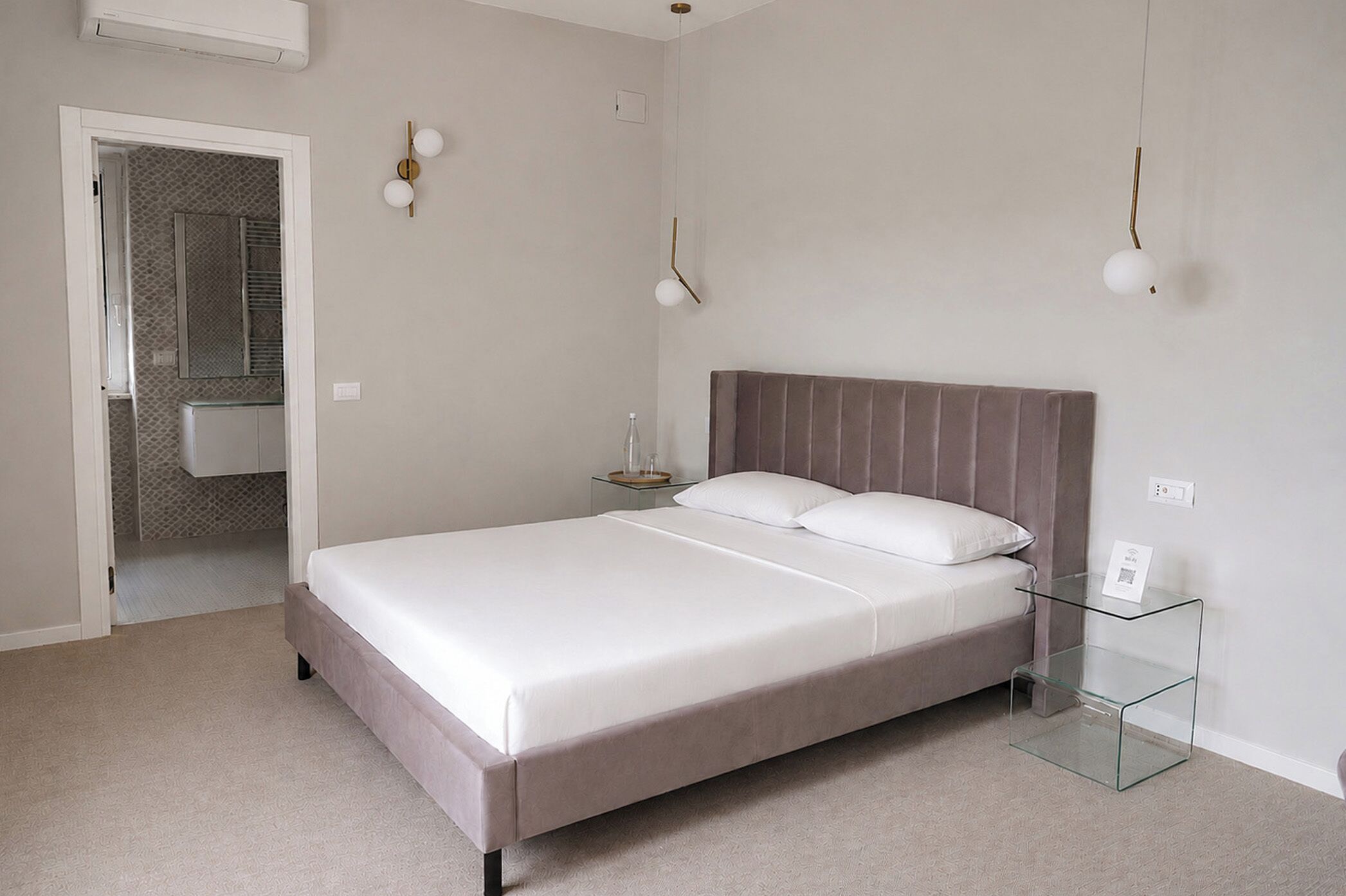 Um quarto com uma cama, mesa de cabeceira e mesa de apoio de vidro.