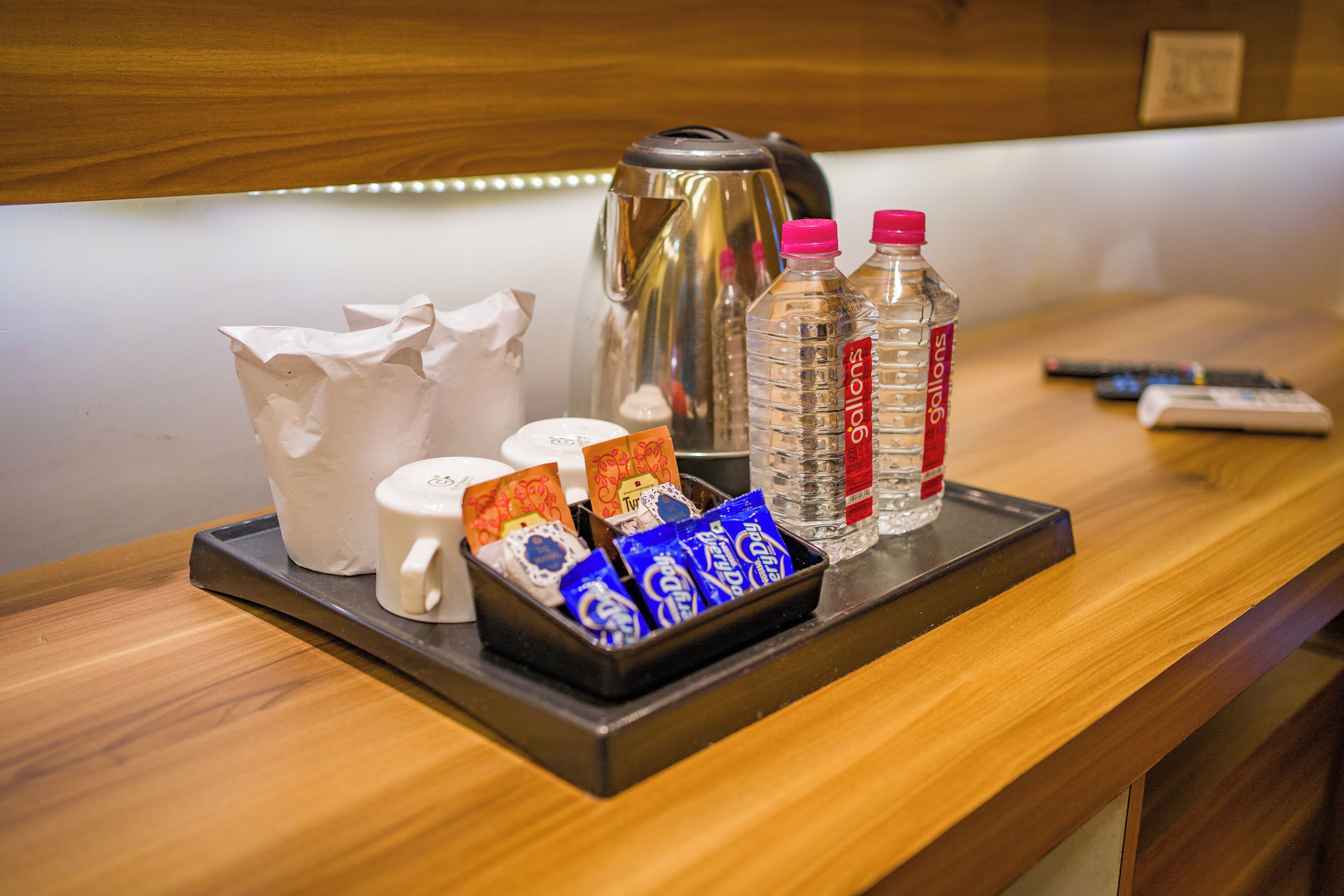 Uma área de recepção de hotel com uma bandeja contendo uma cafeteira, água engarrafada, caixa de lenços e uma bandeja de petiscos.