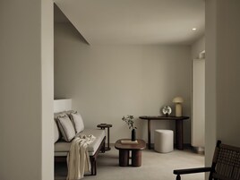 Uma sala de estar moderna e minimalista, com um sofá, mesa de centro e uma pequena mesa lateral com abajur.