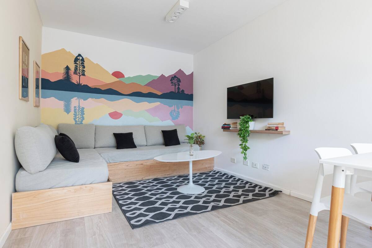 Uma sala de estar moderna com um sofá, uma mesa de centro e um mural na parede.