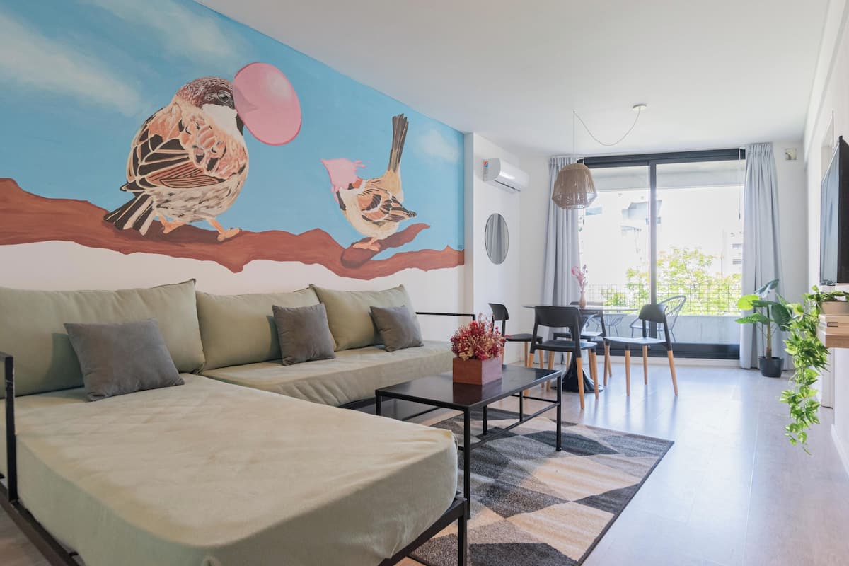 Uma sala de estar moderna com um sofá, uma mesa de centro e um mural de pássaros na parede.