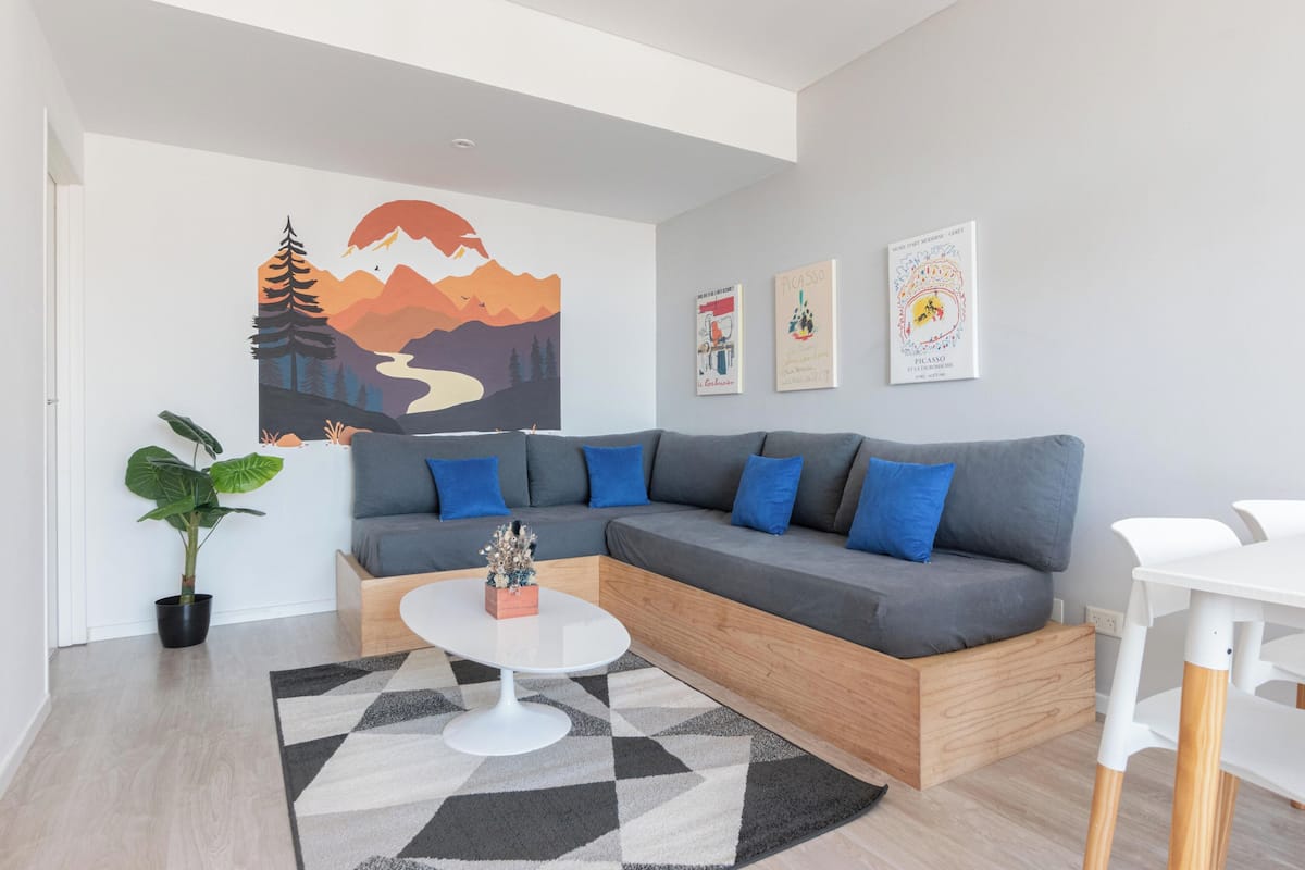 Uma sala de estar moderna com um sofá seccional, uma mesa de centro e uma pintura grande na parede.