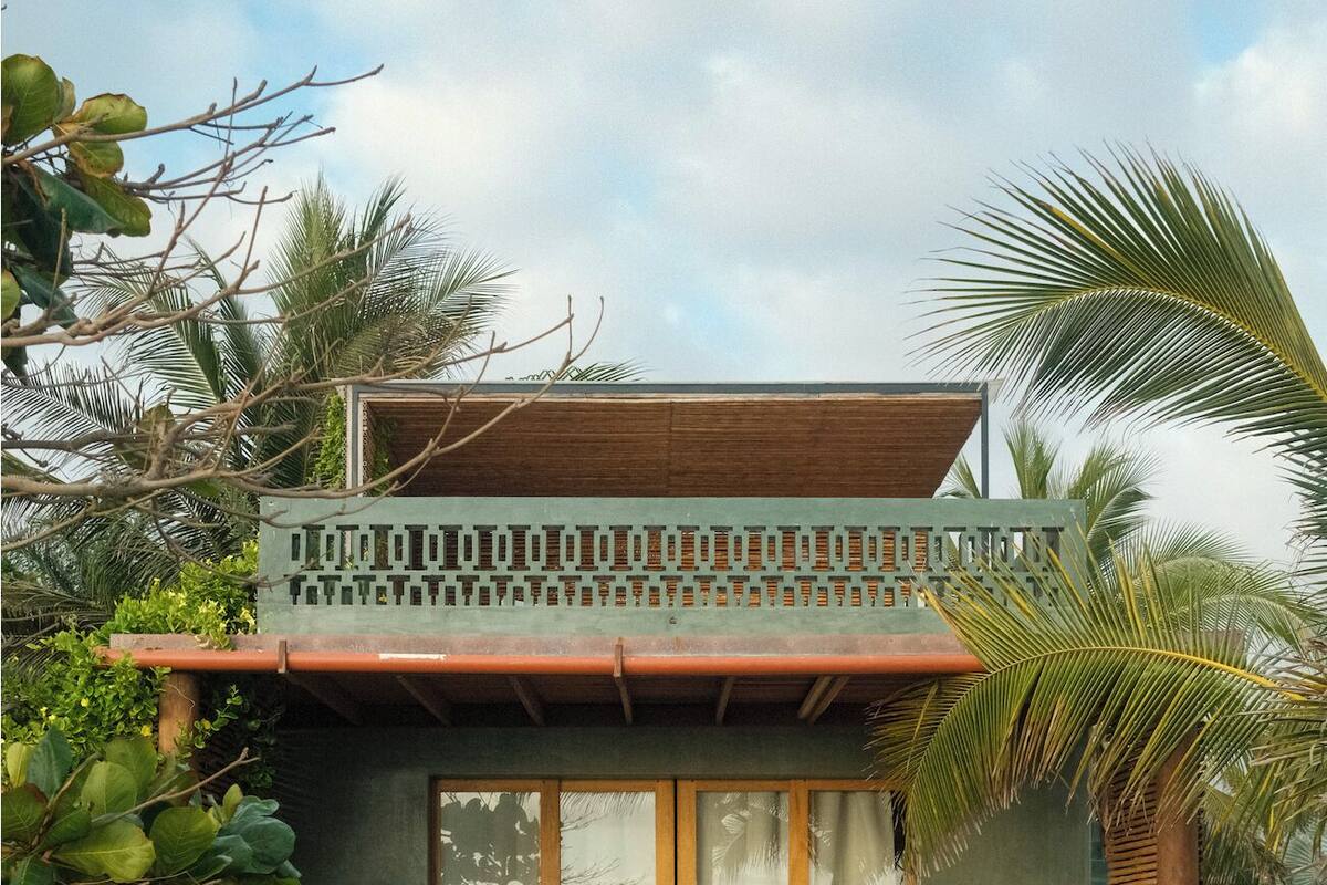 Uma casa moderna com deck de madeira, grandes portas de correr de vidro e uma parede de pedra.
