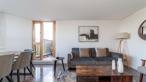 Uma sala de estar com sofá, mesa de centro, cadeiras e um quadro na parede.