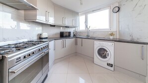 Uma cozinha moderna com fogão de aço inoxidável, micro-ondas e máquina de lavar integrada.