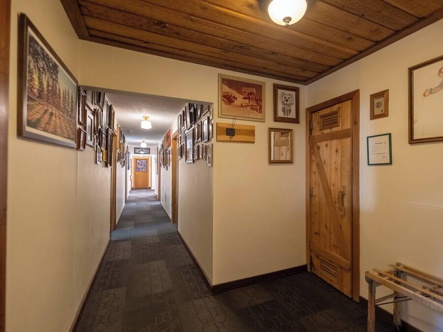 Um corredor com quadros nas paredes, uma porta de madeira e um banco.