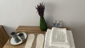 Uma mesa de madeira com um tabuleiro de chá, um vaso de lavanda e duas garrafas de água.