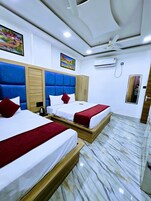 Quarto de hotel com duas camas, ventoinha no teto, ar condicionado e um quadro na parede.