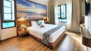 Quarto com uma cama grande, piso de madeira, um quadro de uma praia e uma TV fixada na parede.