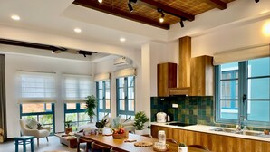 Uma cozinha moderna com ilha de madeira, grandes janelas e área de refeições com cadeiras e mesa.