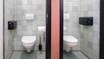 Um banheiro moderno com dois vasos sanitários, uma pia e dois dispensadores de sabão.