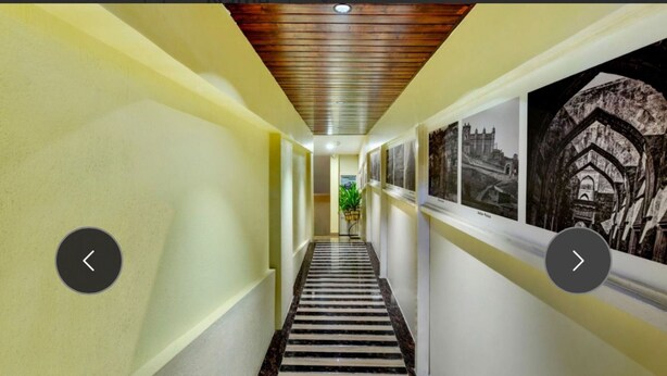 Um corredor com teto de madeira, piso listrado em preto e branco e quadros nas paredes.