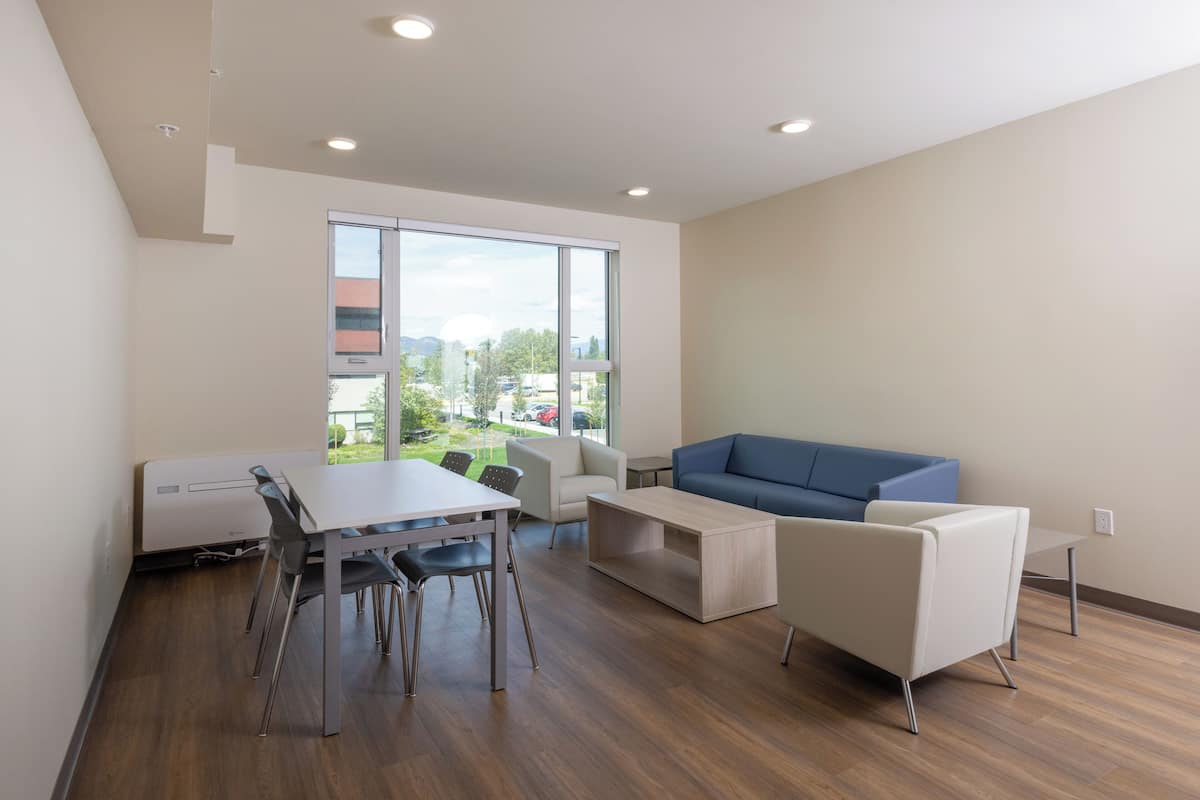 Uma sala de estar moderna com área de jantar, janelas amplas e vista para o exterior.