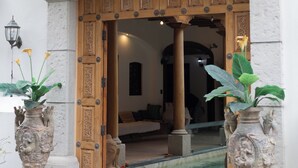 Uma entrada imponente com porta de madeira e colunas, dando acesso a um espaço interior bem iluminado.