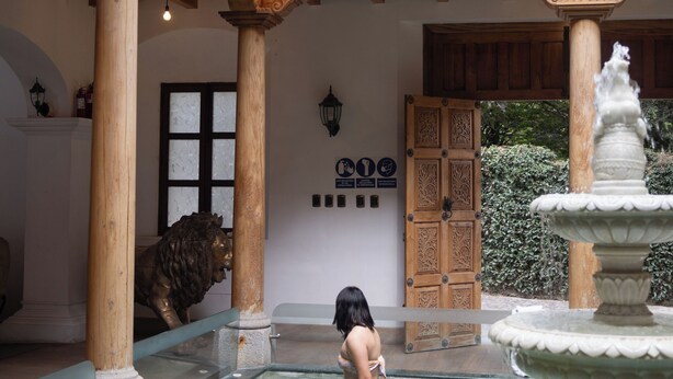 Uma área de spa com hidromassagem, uma fonte e vigas de madeira.