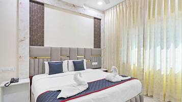 Quarto de hotel moderno com uma cama grande, telefone ao lado da cama e cortina com padrão discreto.