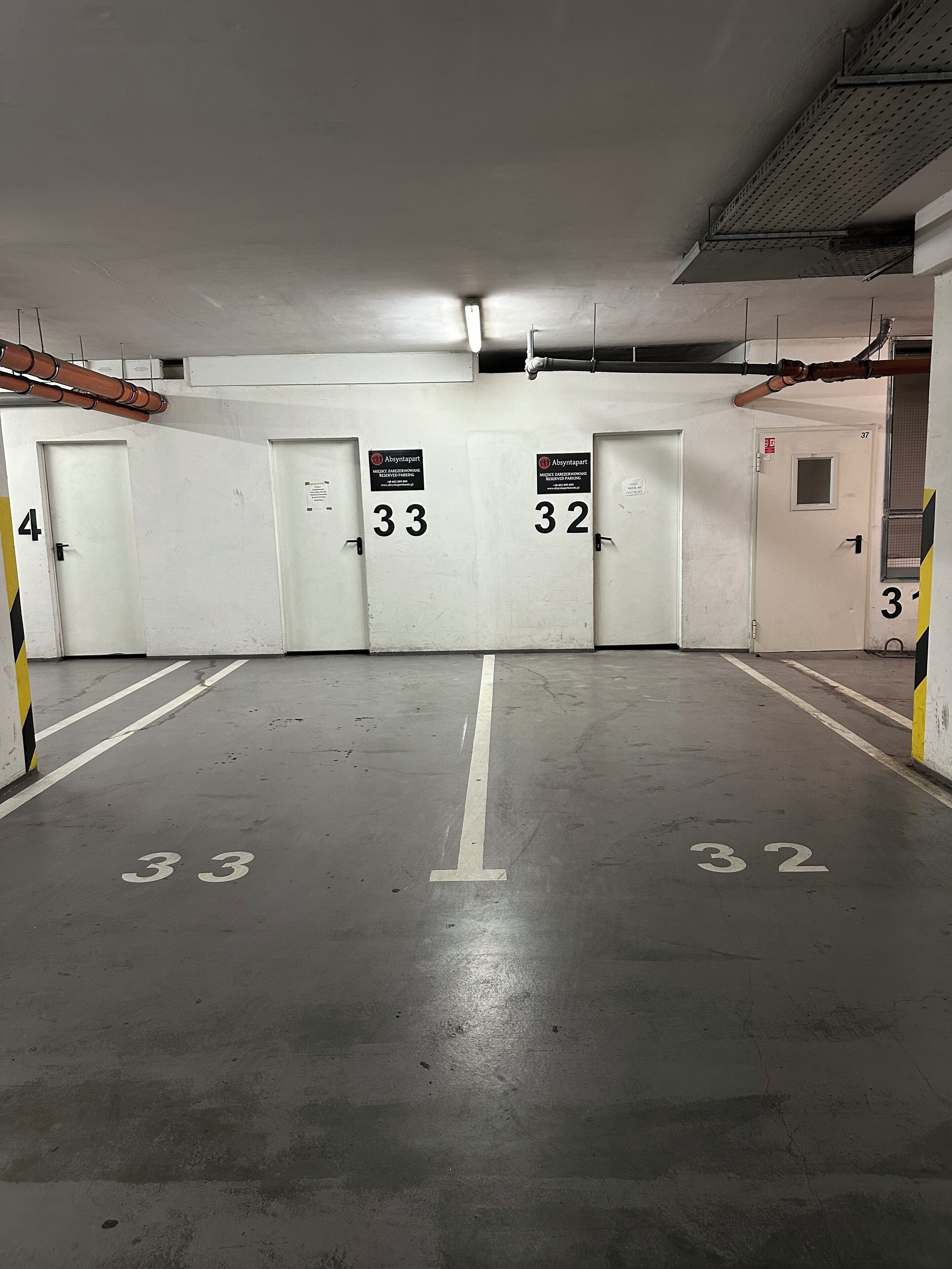 Uma garagem de estacionamento com vagas numeradas 33 e 32, e uma porta com a inscrição 37.