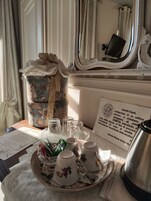 Uma mesa posta com xícaras, pires e bule de chá, uma cesta estampada com motivos florais e um cardápio.