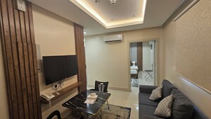 Uma sala de estar moderna com televisão de tela plana, uma mesa de jantar e um sofá.